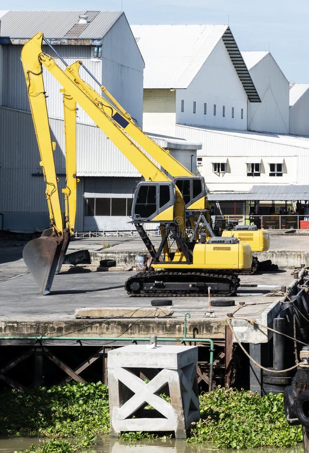 Two yellow backhoe on dock stock image. Image of vessel - 256399003