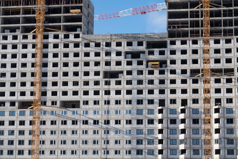 Two Yellow Construction Cranes on the Facade of a Tall Building Under ...