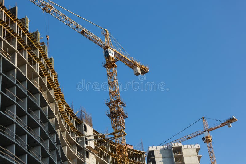 Two Yellow Construction Cranes Running Near the House Under ...