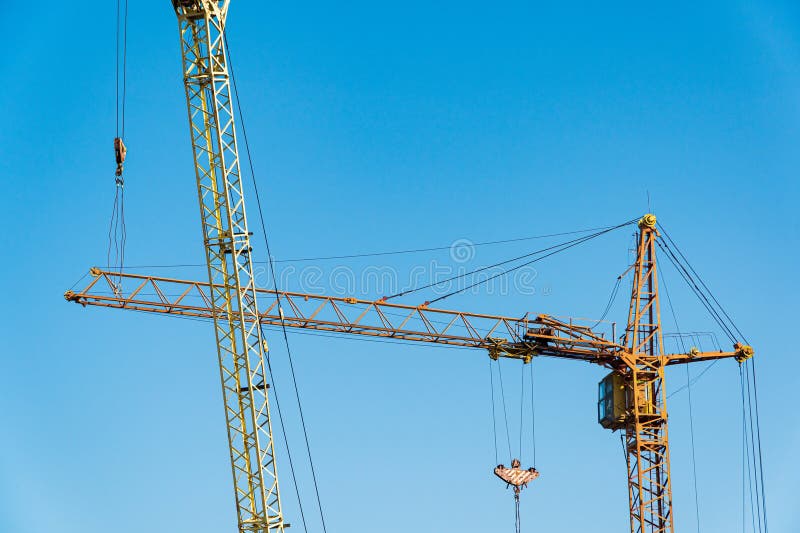 Two Yellows Hoisting Cranes with Blue Sky Background. Machines for ...