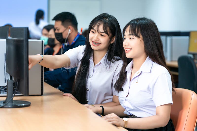Young Asian Female Students are Seated at a Desk, Interacting with a ...