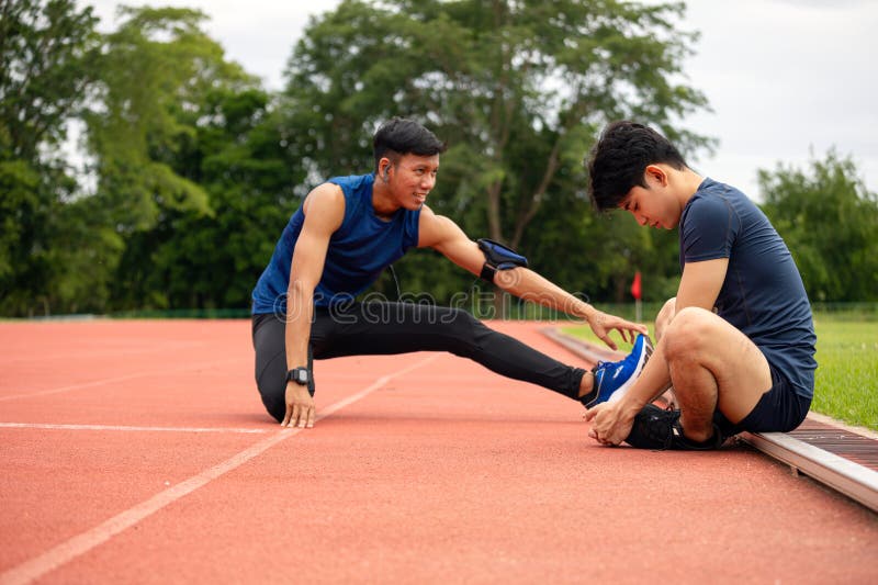 Two Young Men Stretching Together on Outdoor Running Track, Post ...