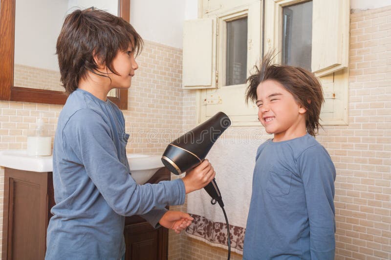 Two Young Boys are Drying Their Hair with a Blow Dryer Stock Image ...