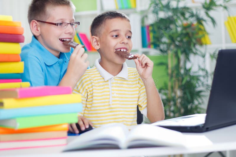 Two Young Boys Eating Chocolate and Using Laptop Stock Image - Image of ...