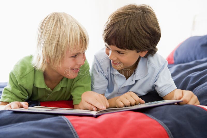 Two Young Boys Lying Down on a Bed Reading a Book Stock Image - Image ...