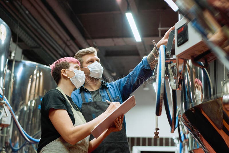 Two Young Brewers of Beer Production Factory Looking at Control Panel ...
