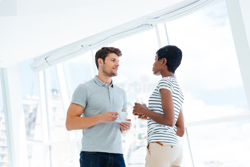 Two Young Business People Standing and Talking in Office Stock Photo ...