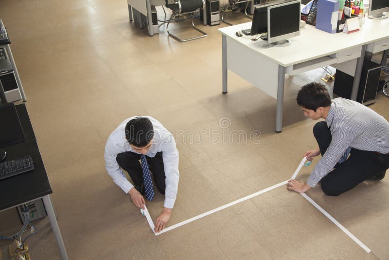 Two Young Businessmen Taping Up the Floor in the Office Stock Photo ...