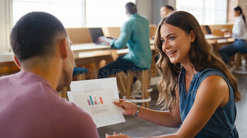 Two Young Businesspeople Meeting in Office Discussing Documents with ...