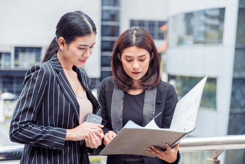 Two Young Businesswomen Looking into Document File Folder for Analyzing ...
