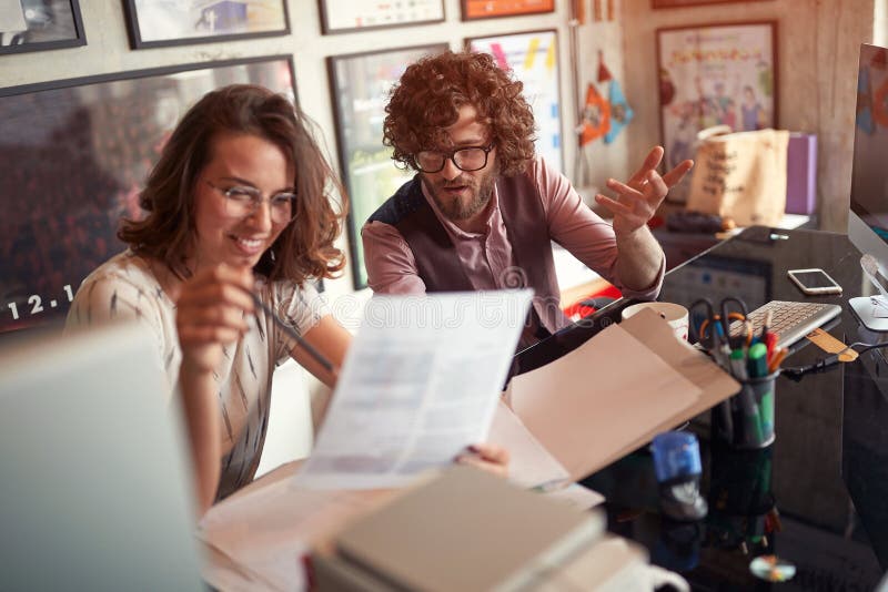 Two of Young Colleagues are Reading and Discussing Some Documents while ...
