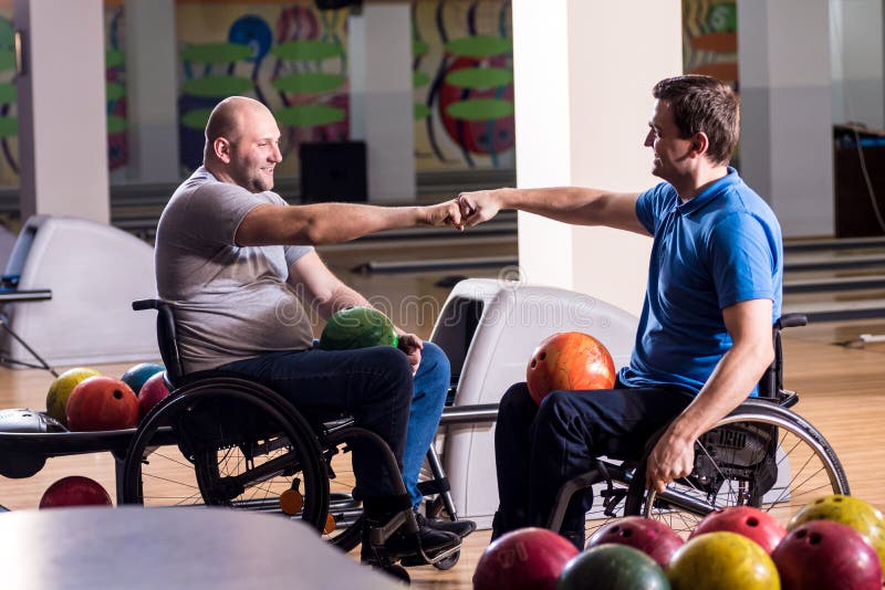 Two Young Disabled Men in Wheelchairs Playing Bowling in the Club Stock ...