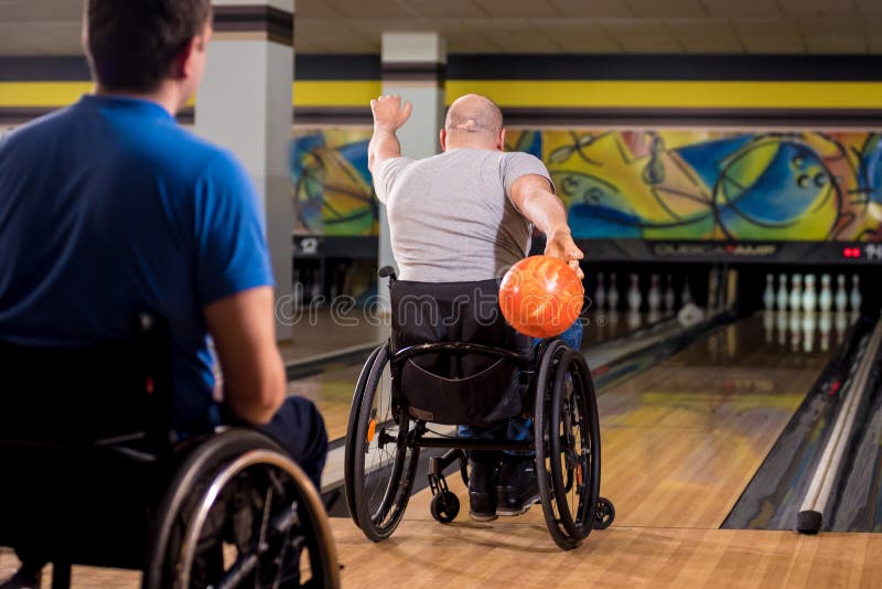 Two Young Disabled Men in Wheelchairs Playing Bowling in the Club Stock ...