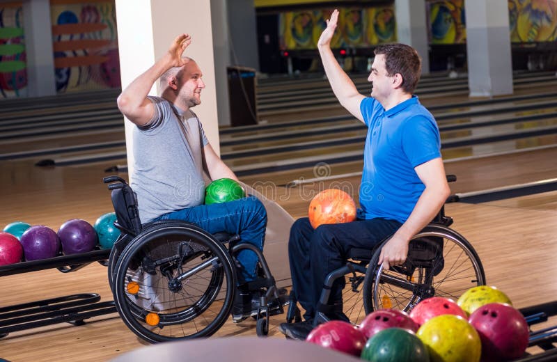 Two Young Disabled Men in Wheelchairs Playing Bowling in the Club Stock ...
