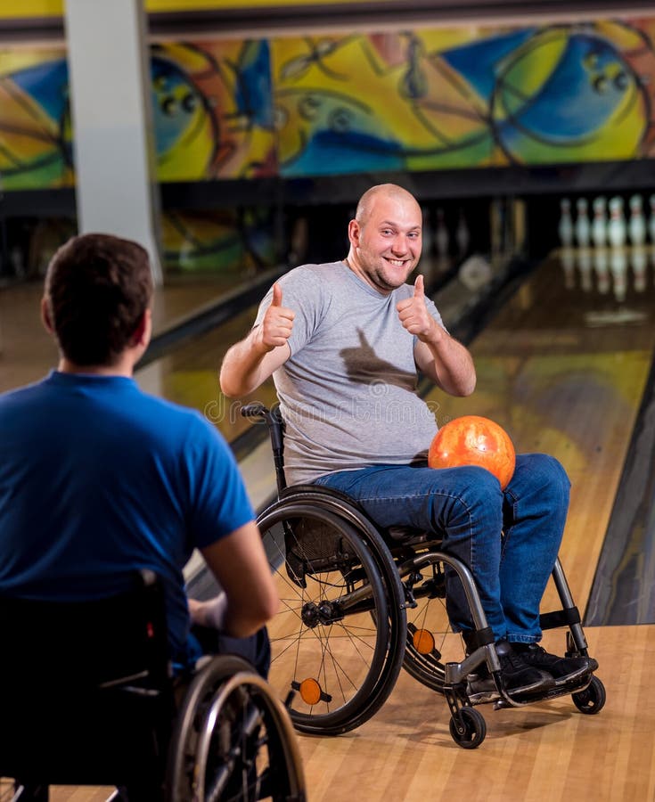 Two Young Disabled Men in Wheelchairs Playing Bowling in the Club Stock ...