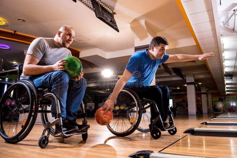 Two Young Disabled Men in Wheelchairs Playing Bowling in the Club Stock ...