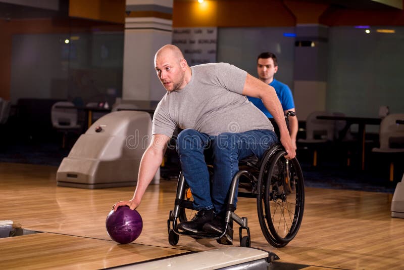 Two Young Disabled Men in Wheelchairs Playing Bowling in the Club Stock ...