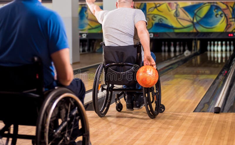 Two Young Disabled Men in Wheelchairs Playing Bowling in the Club Stock ...