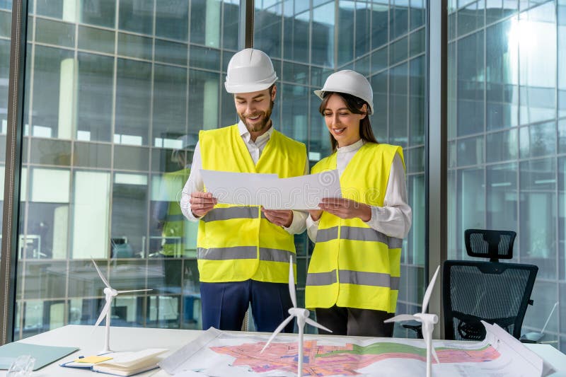 Two Young Engineers in Yellow Vests Discussing New Sustainability ...