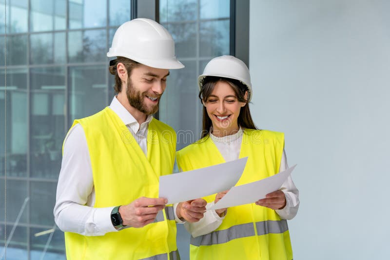 Two Young Engineers in Yellow Vests Discussing New Sustainability ...