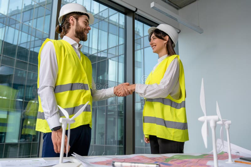 Two Young Engineers Yellow Vests Shaking Hands Working Together Stock ...