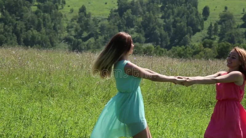 Video: Two young girlfriend circling hand in hand on the green meadow ...