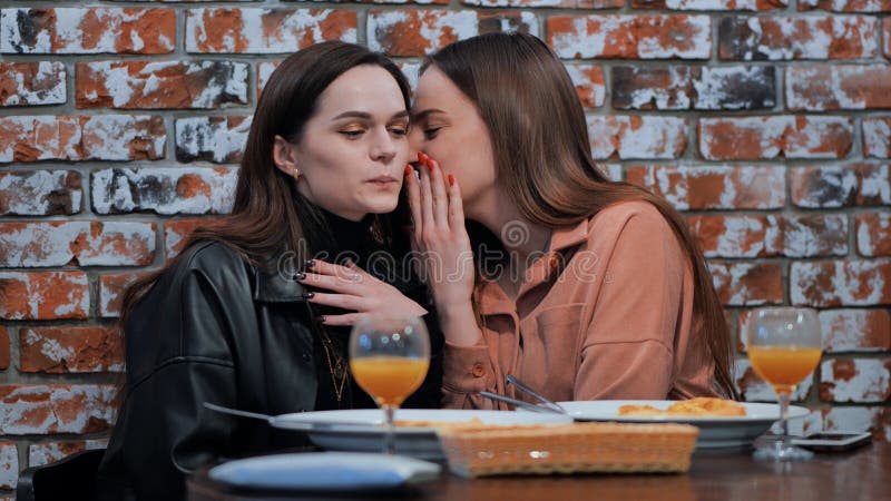 Two Young Girls Gossiping Sitting in a Cafe. Stock Image - Image of ...
