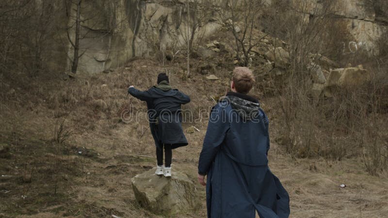 Two Young Guys Running Forward. Guys in Raincoats on Rock Background ...