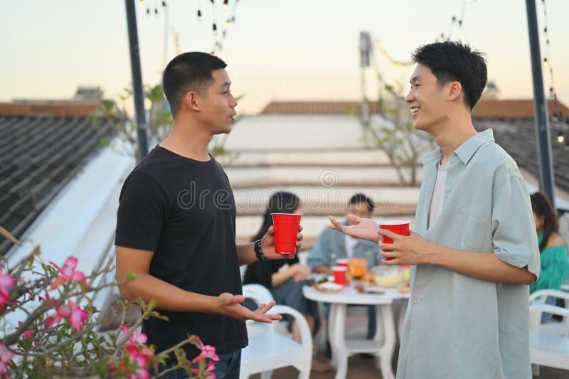 Two Young Handsome Men Having Drinks and Chatting at the Rooftop Party ...