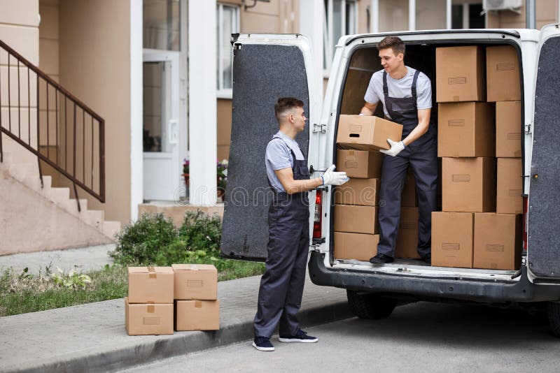 Two Young Handsome Movers Wearing Uniforms are Unloading the Van Full ...