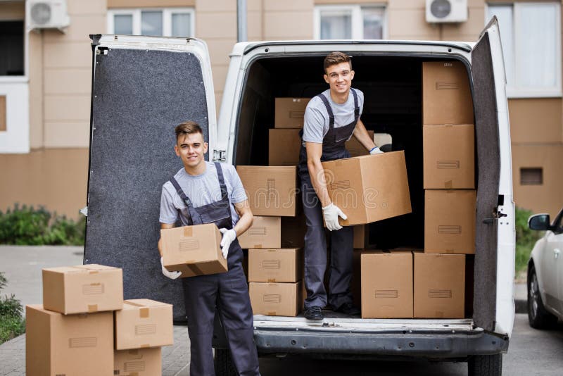 Two Young Handsome Smiling Movers Wearing Uniforms are Unloading the ...