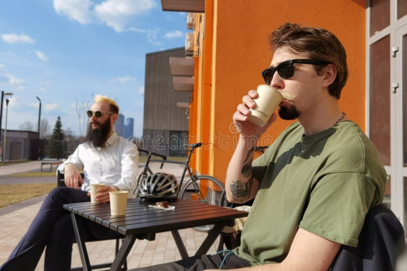 Two Young Hipster Guy Sitting in a Cafe Chatting and Drinking Coffee ...