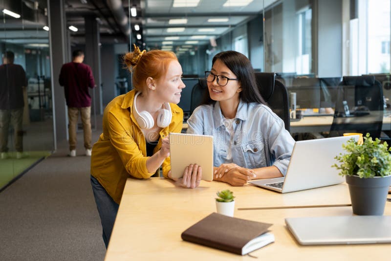 Two Young Intercultural Female Managers Looking at One Another with ...