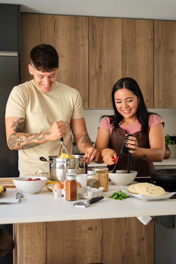 Two Young Latin People Mashing Potatoes and Grating Tomato at Kitchen ...