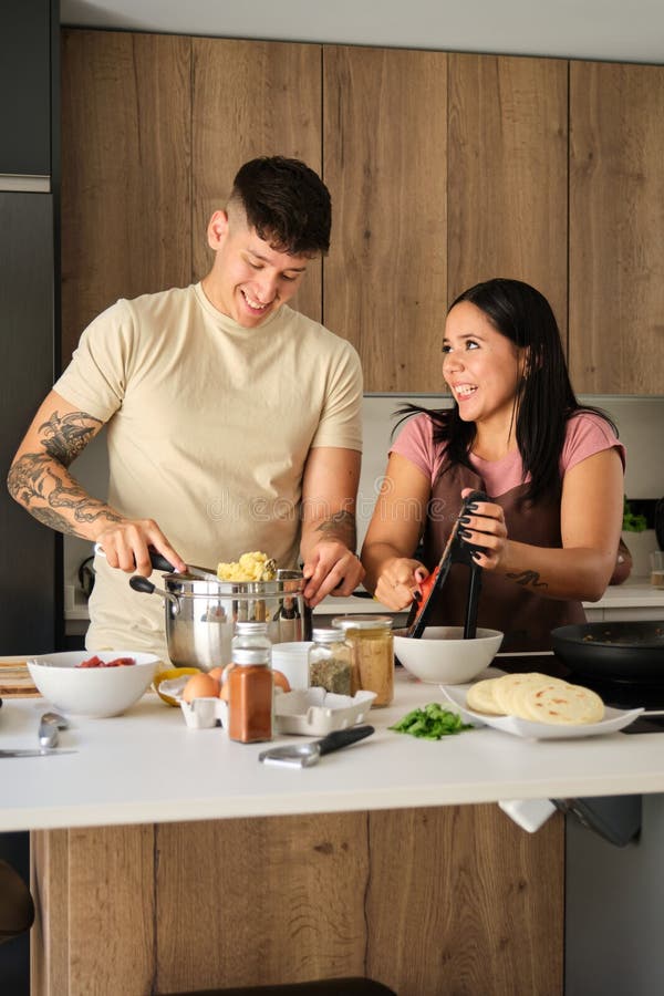 Two Young Latin People Mashing Potatoes and Grating Tomato at Kitchen ...