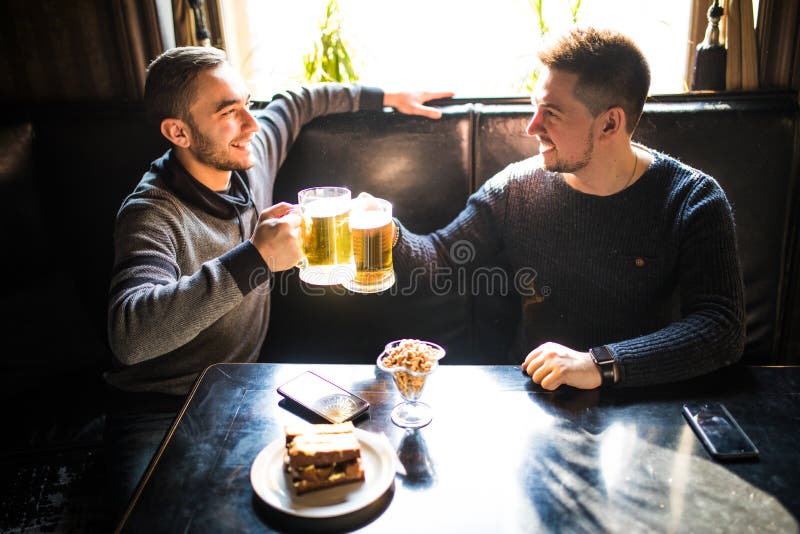 Two Young Man Sitting in Pub, Eating and Drinking Beer at Pub Stock ...