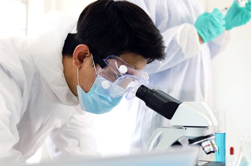 Two Young Men Scientist Using a Microscope for Looking Solution in ...