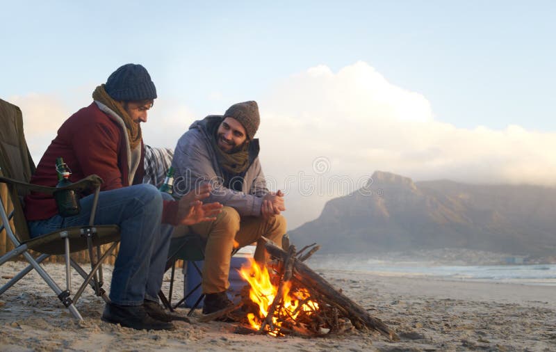 Its Warming Up Fast. Two Young Men Sitting Around a Fire on the Beach ...