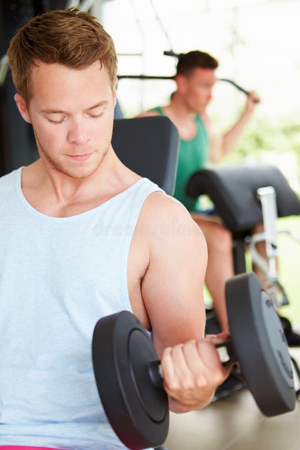 Two Young Men Training in Gym on Cycling Machines Together Stock Photo ...