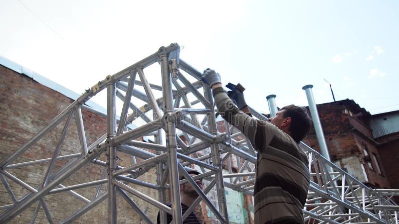 Two Young Men Workers are Setting Grey Metallic Stage Structure Outside ...