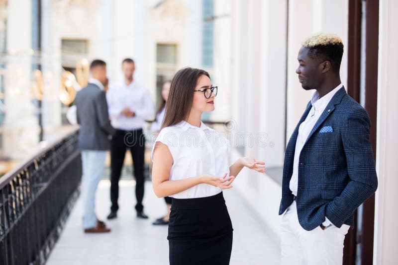 Two Young Mixed Race Colleagues Discussing in Front Their Business Team ...