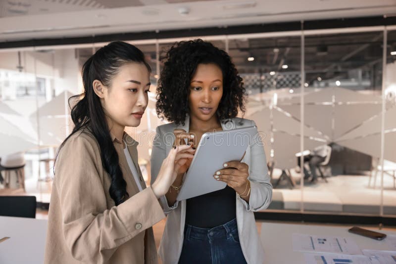 Two Young Multiethnic Women Workmates Using Tablet Standing in ...