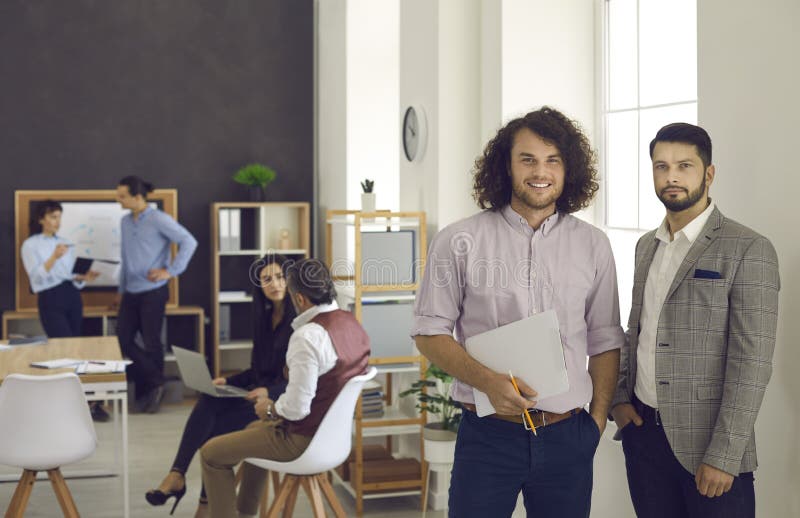 Two Young Office Colleagues Smiling at the Camera, Holding Documents ...