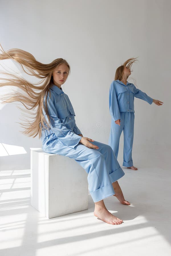 Two Young Pretty Twin Sisters with Waving Hair Posing in Blue Suits on ...