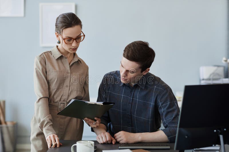 Two Young Professionals Looking at Clipboard Reviewing it Project in ...
