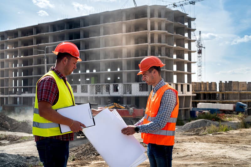 Two Young Smart Workers in Uniform Standing on a Construction Site ...