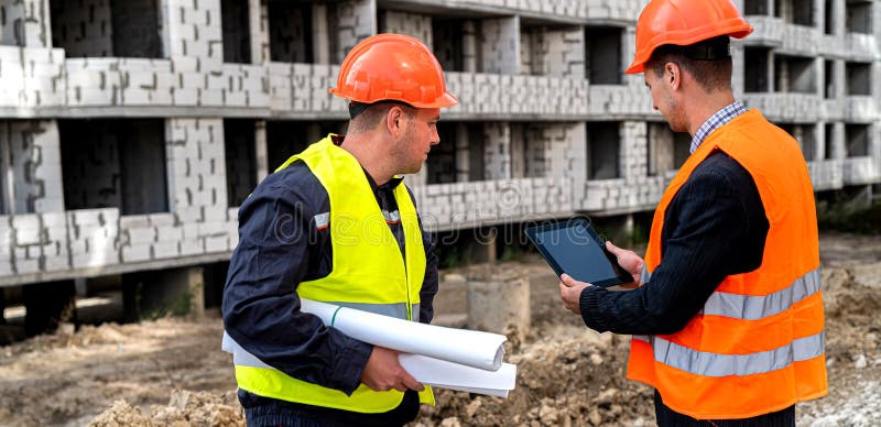Two Young Smart Workers in Uniform Standing on a Construction Site ...