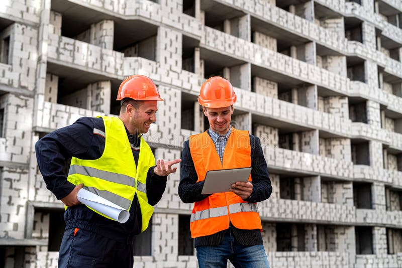 Two Young Smart Workers in Uniform Standing on a Construction Site ...
