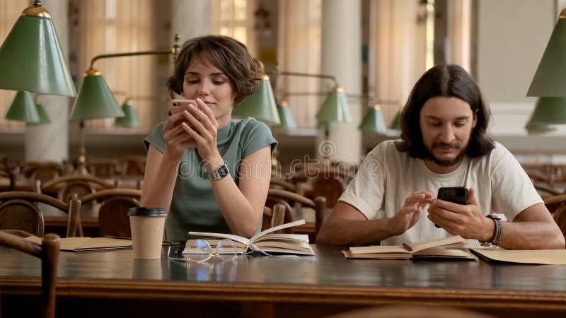 Two Young Students Intently Using Smartphones while Preparing for Exams ...