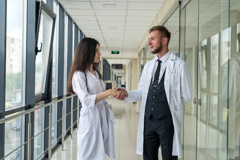 Two Young Trainee Doctors Pose in the Corridor of a Modern Hospital ...